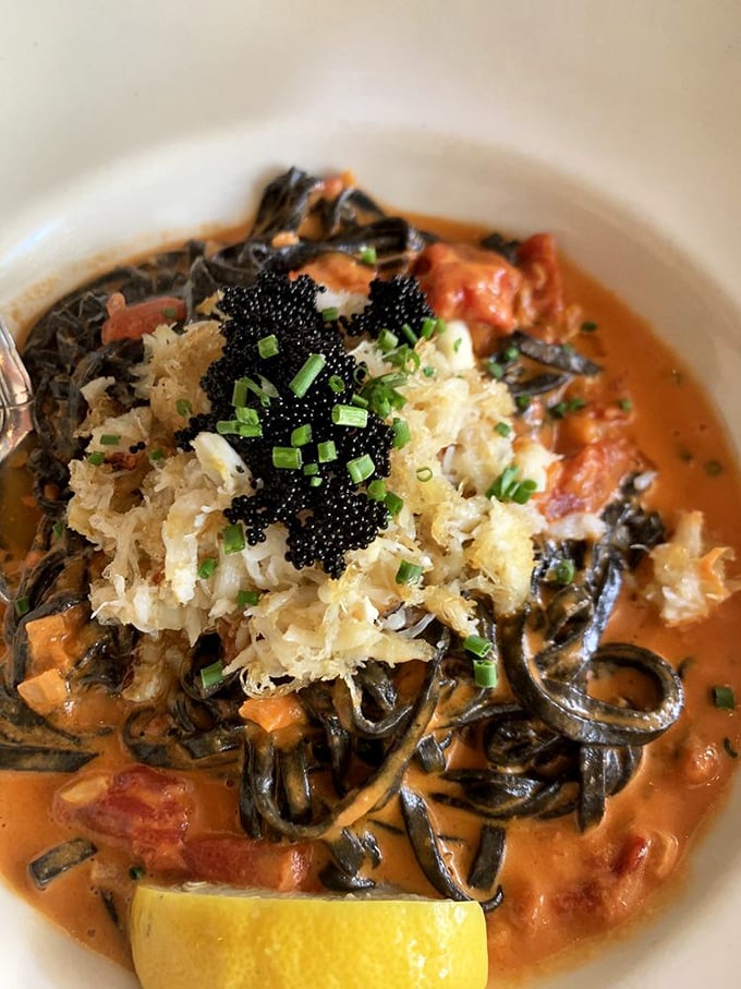 Squid ink pasta that looks like midnight ocean waves carrying treasures of seafood and tomato cream. Eating it feels slightly rebellious and entirely right.