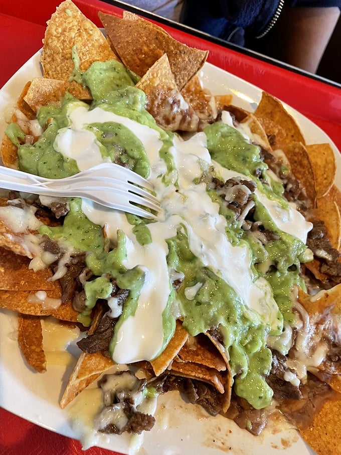 Nachos aren't just a snack here—they're a full-fledged meal with layers of chips, meat, cheese, and guacamole creating a mountain of deliciousness.
