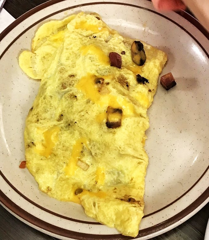This omelet doesn't just contain ingredients—it embraces them in a fluffy yellow hug of breakfast perfection.