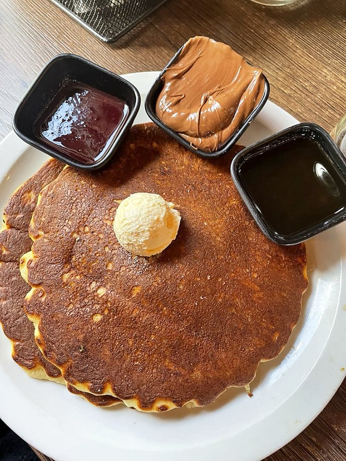 These pancakes arrive with three sidekicks—chocolate, peanut butter, and maple syrup—forming a breakfast dream team.