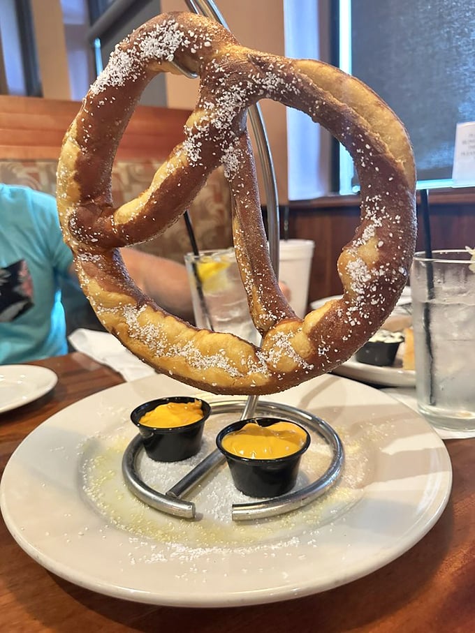 This pretzel isn't just big, it's architectural – suspended in mid-air like carb performance art with dipping sauces standing by for duty.