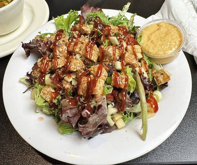 A salad that doesn't apologize for being healthy—those crisp greens proudly supporting what appears to be tempeh in barbecue sauce.