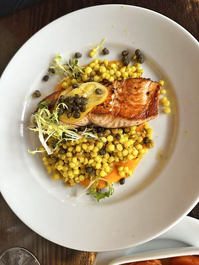 Perfectly seared salmon atop golden pearls of couscous and capers—ocean meets farmland in a dish that practically demands a glass of white wine.