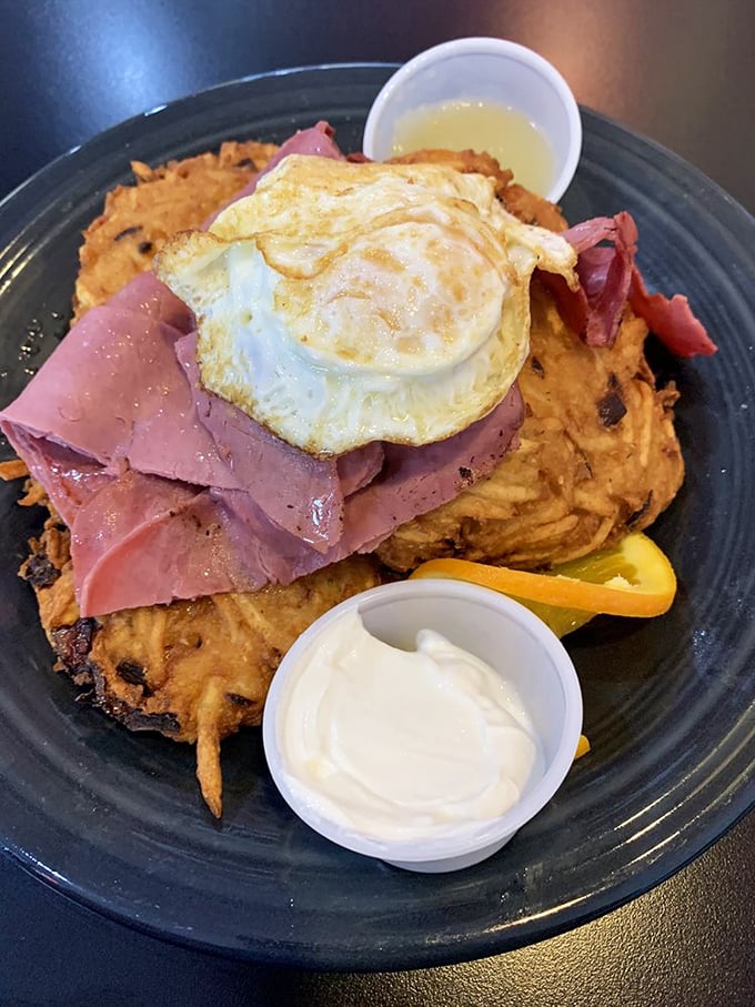 The Schmoozer plate showcases sweet potato hash browns topped with ham and a perfectly fried egg—a tower of breakfast glory that demands to be photographed.