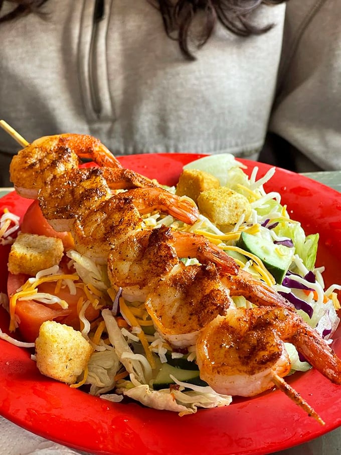 Grilled shrimp skewer perched atop a colorful salad—proof that healthy eating doesn't have to be punishment. Those char marks tell the real story.