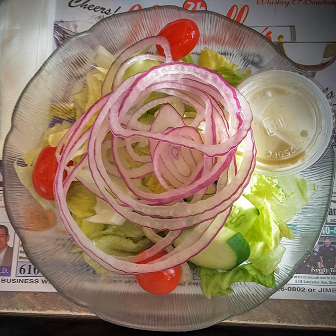 A garden of red onions blooming atop fresh greens—proof that even the side salad gets the star treatment at Minella's.