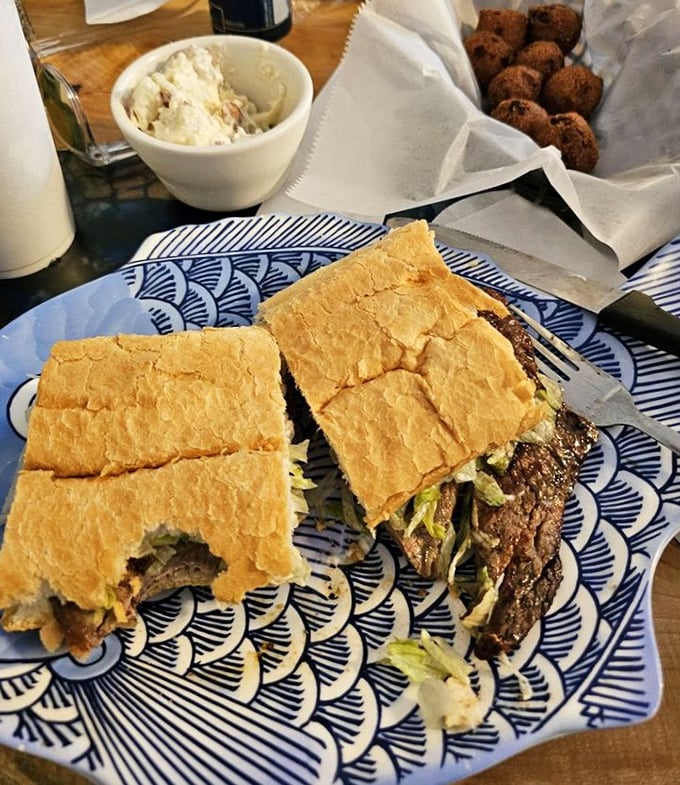 A proper steak po-boy served on blue-patterned plates – because sometimes the best steakhouse experience comes between two pieces of bread.
