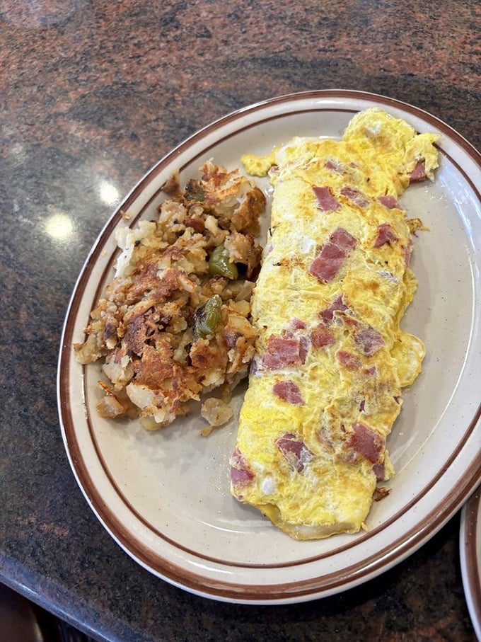 This isn't just an omelet—it's a morning masterpiece where ham cubes play hide-and-seek in a fluffy yellow landscape of perfectly cooked eggs.