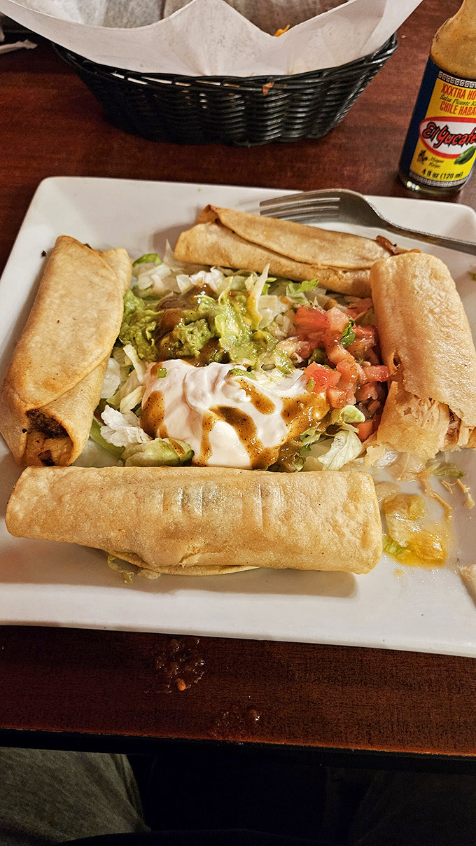 Four golden flautas standing at attention around a fresh salad. The sour cream dollop in the middle is the general, commanding your taste buds to attention.