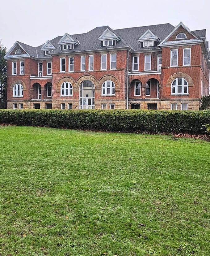 Manicured hedges and tidy landscaping can't quite mask the haunting presence of this imposing brick structure with its watchful windows.