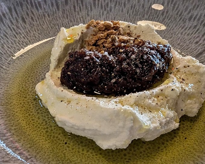 This isn't just dessert, it's an edible sculpture—whipped ricotta cradling dark, rich morsels that demand to be savored slowly.