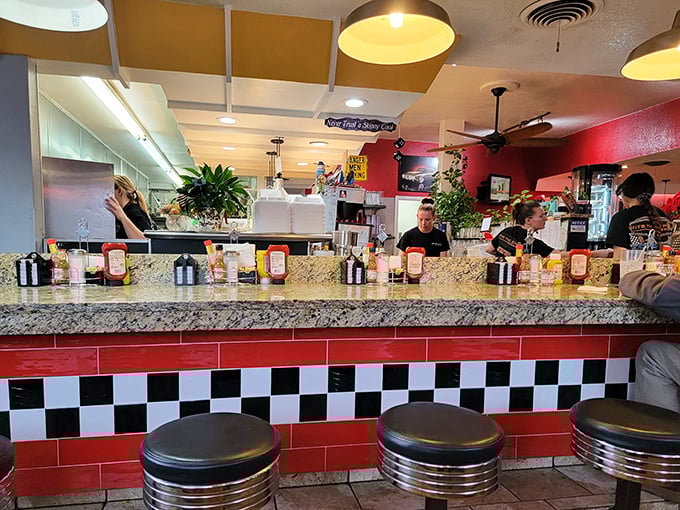 The diner counter—where solo diners become temporary family and the red-and-white checkerboard pattern screams "authentic American experience."