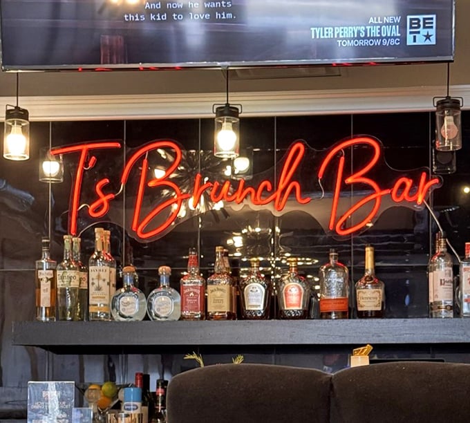 The neon "T's Brunch Bar" sign glows like a beacon above a well-stocked bar—because sometimes pancakes need a little liquid companionship.