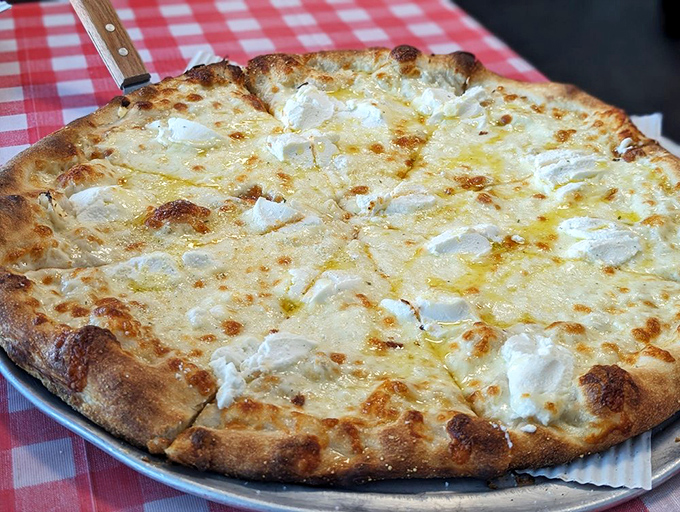 The white pizza that proves sometimes less is magnificently more. Creamy cheese islands on a sea of garlic-infused olive oil—simplicity at its finest.