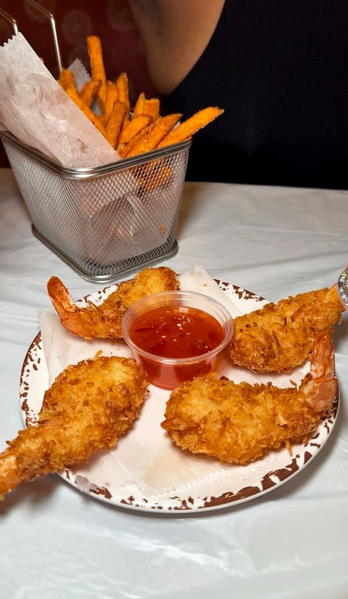 Coconut shrimp that could convert seafood skeptics—crispy, golden, and served with a dipping sauce that makes you consider drinking it straight.