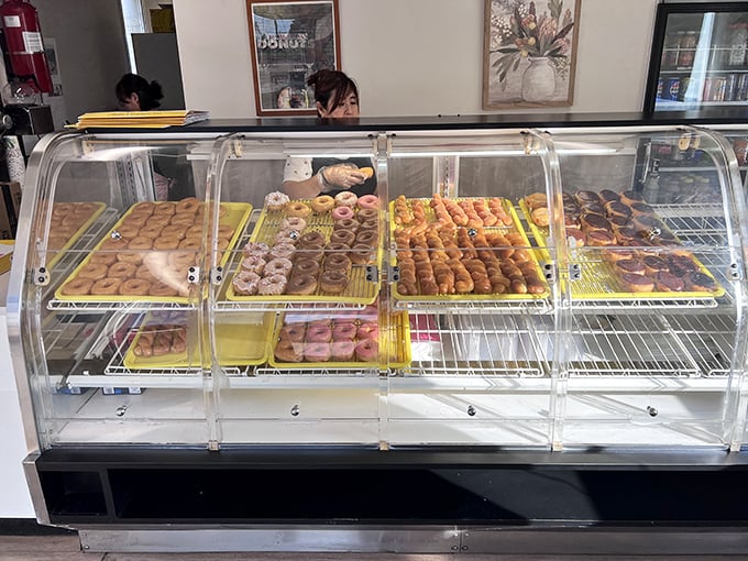 Behind the glass lies a rainbow of donut possibilities, each tray a different chapter in the story of your expanding waistline.