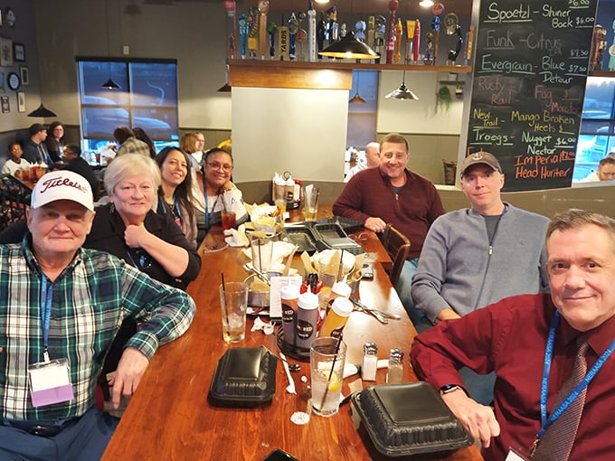 Happy diners gathered around a table laden with barbecue – the universal language of "this was worth the drive" written across every smiling face.