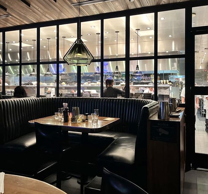 The open kitchen design isn't just trendy—it's dinner and a show, with the glass partition offering a glimpse into the culinary choreography.