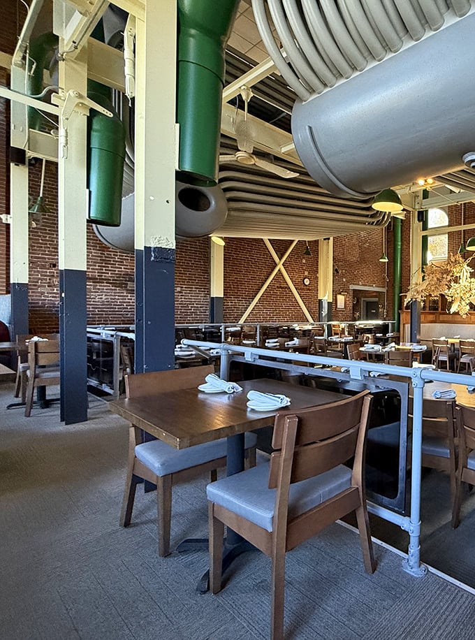 Every table offers a view of industrial history with those signature pipes overhead—functional elements transformed into conversation-starting design features.