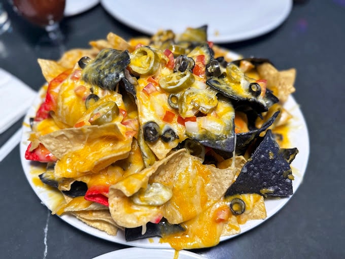 Nachos that require a topographical map to navigate – layers of cheese, jalapeños, and olives creating a mountain range of Tex-Mex magnificence.