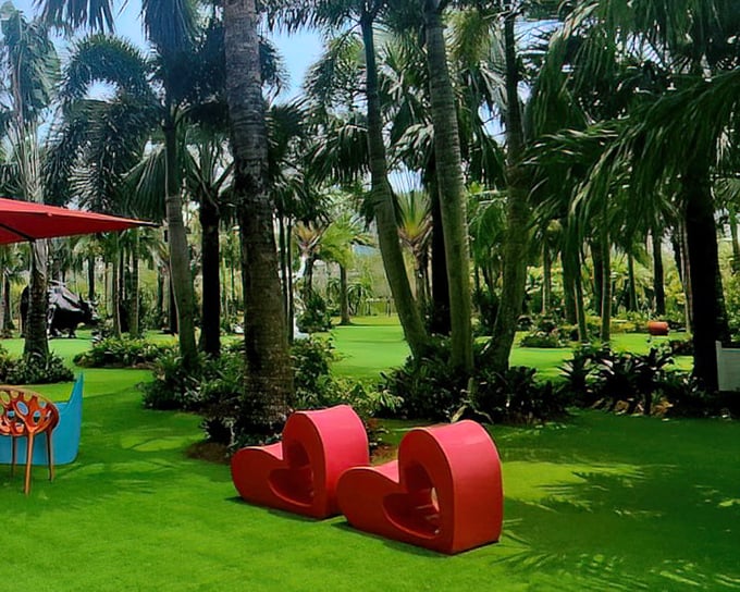 Vibrant red heart sculptures pop against the lush green landscape, offering both artistic appeal and perfectly Instagram-worthy seating for weary art enthusiasts.