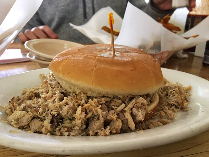 The open-faced pork sandwich doesn't hide behind pretense—just a humble bun absolutely overwhelmed by a glorious heap of smoky meat.