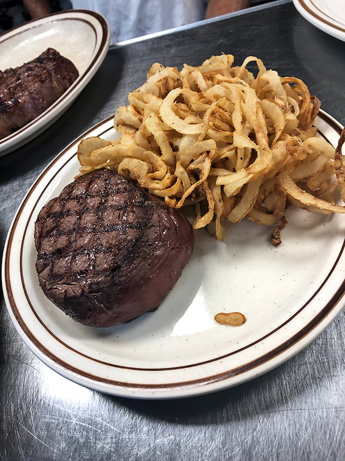 A perfectly cooked filet mignon alongside a mountain of crispy onion straws—a classic pairing that never goes out of style for very good reason.