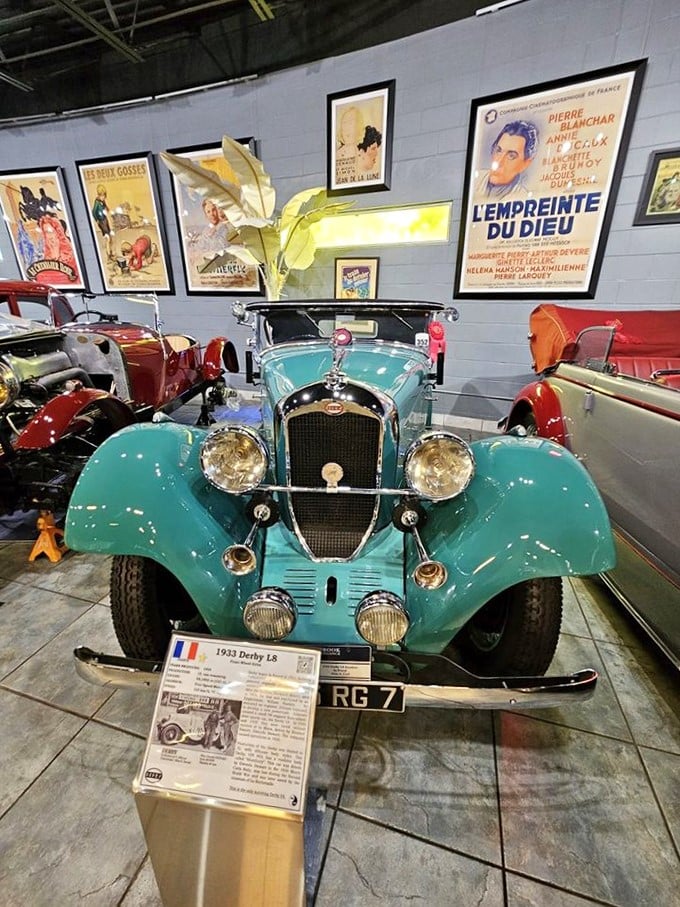 The 1933 Derby L8's turquoise finish pops against the vintage posters. Its gleaming grille smiles at visitors like it's just won a prestigious concours d'elegance.