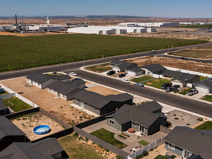 Othello's new housing development: where cookie-cutter dreams meet agricultural reality—backyard barbecues with views of cornfields and industrial tanks. Pure American poetry!